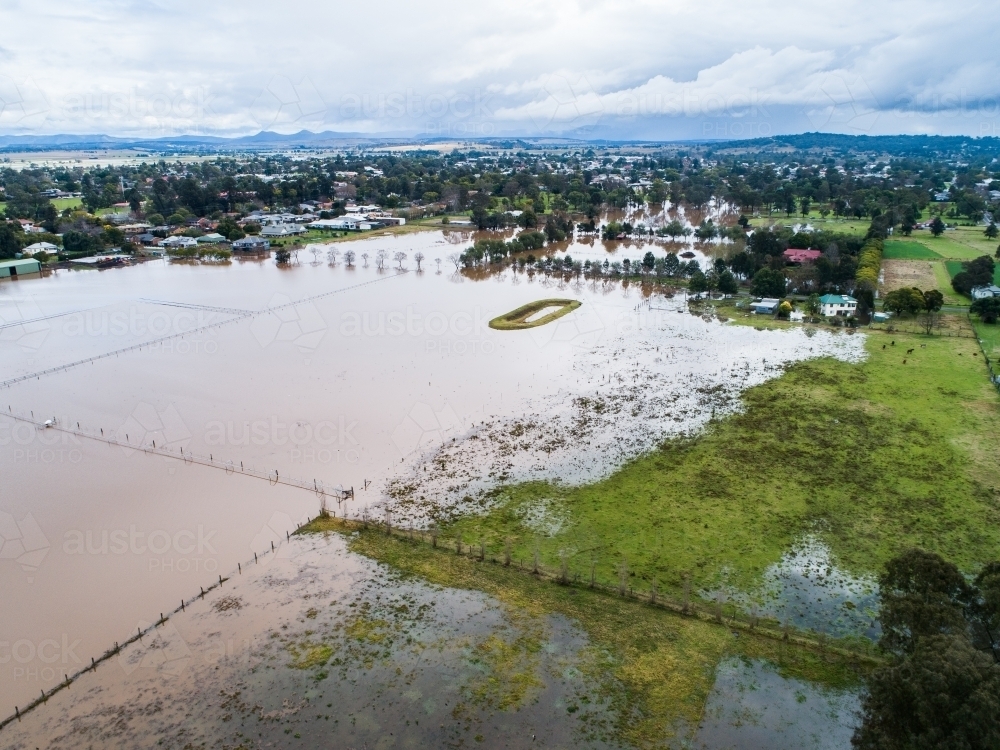 Image of Farm paddocks at edge of town underwater during natural ...