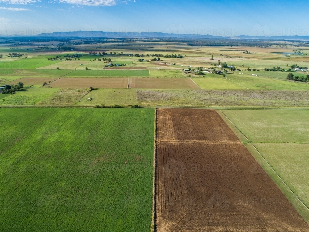 Image of farm paddocks with distant highway leading out of town ...