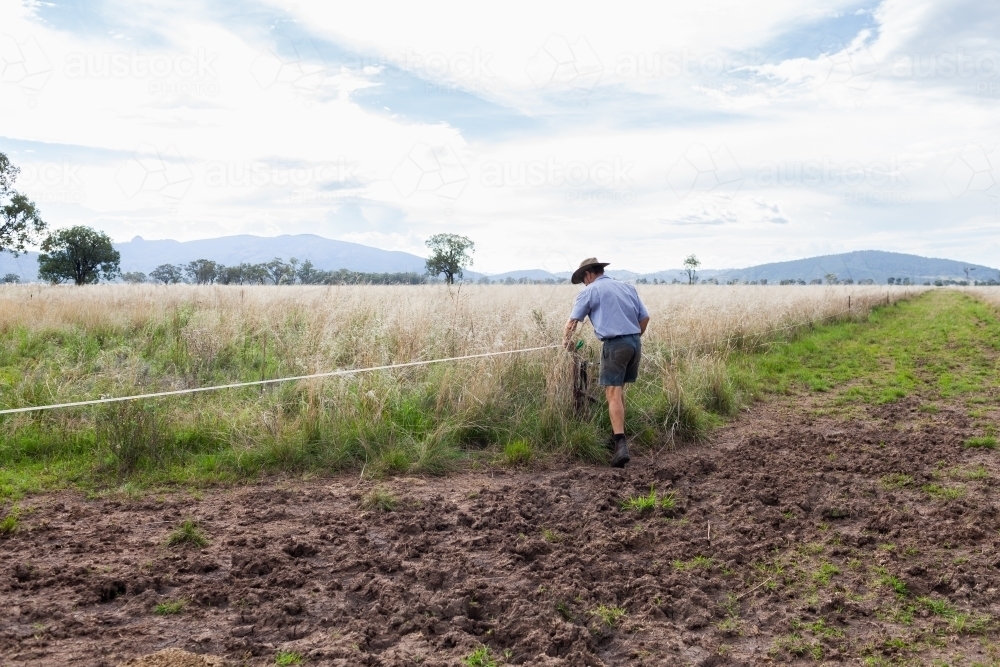 Image of Farmer adjusting electric wire fencing on farm using ...