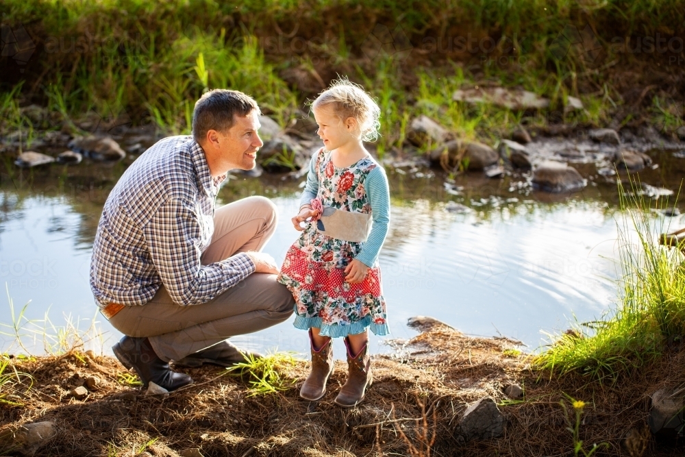 Image of Farmer dad down by the creek with his daughter smiling ...