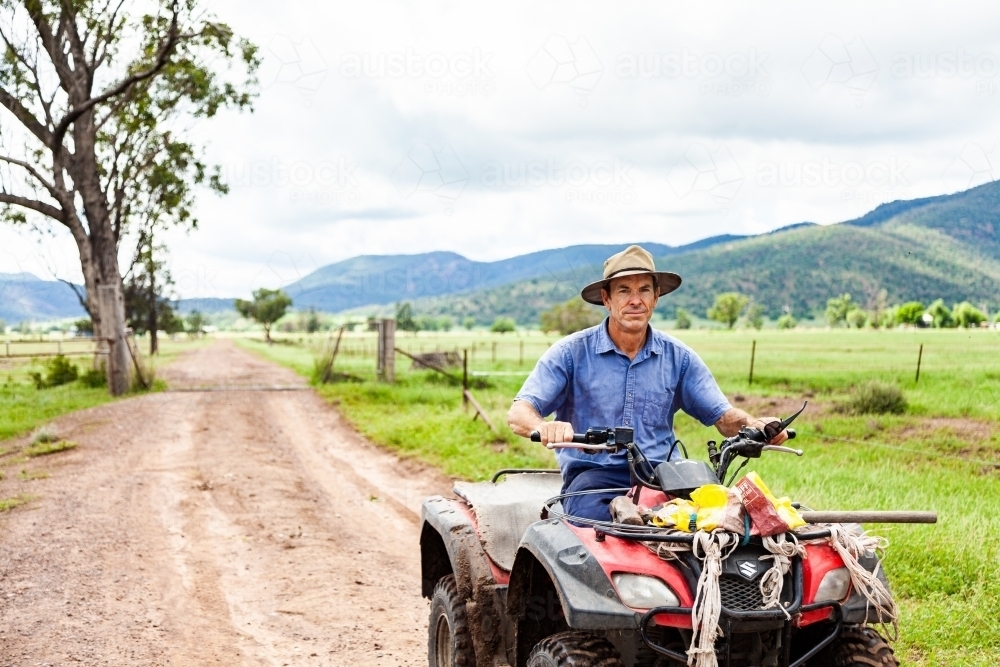 Image of Farmer riding quad bike down farm driveway over cattle grid ...