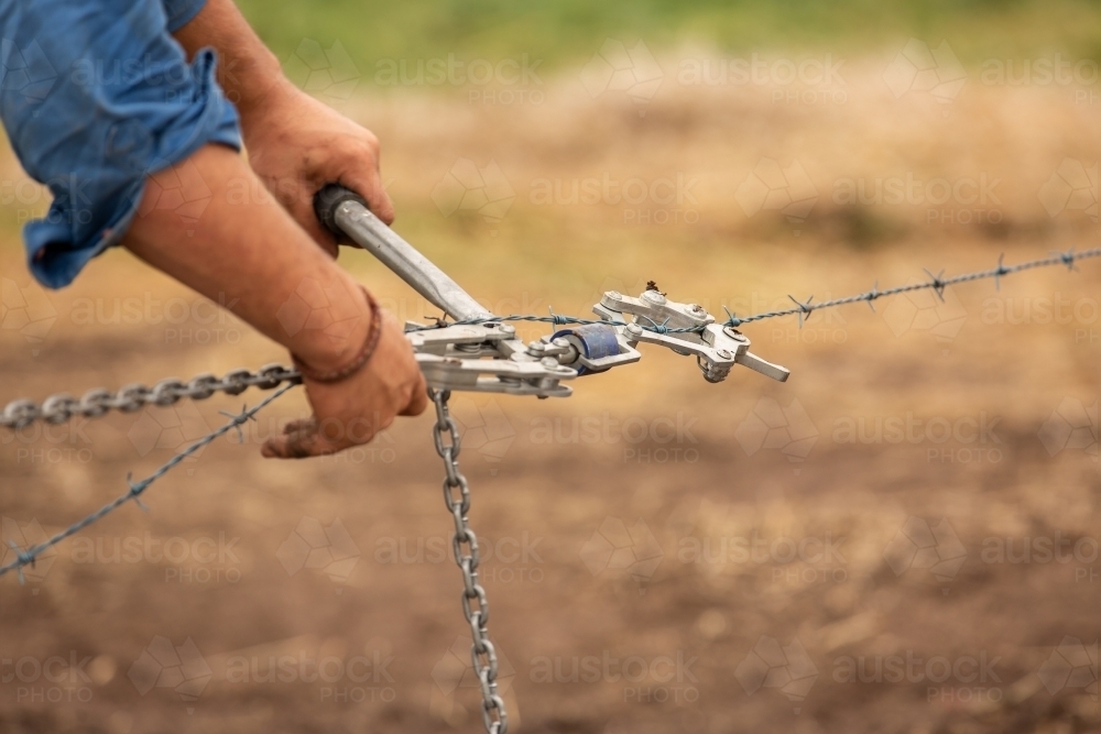 Image of Farmer's hands working a wire strainer while fencing ...