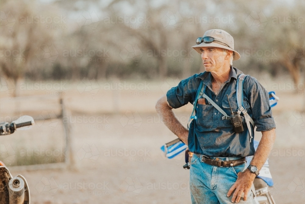 Image of Farmer working in paddock near motorbike - Austockphoto