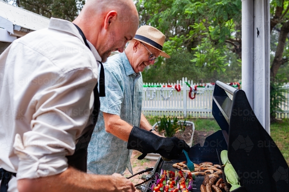 Image of Father and adult son cooking bbq lunch together in backyard of ...