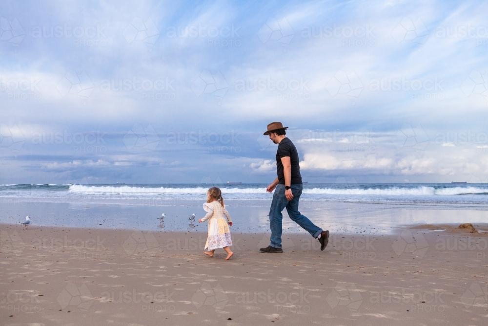 Image of Father and daughter running along the seashore in overcast ...