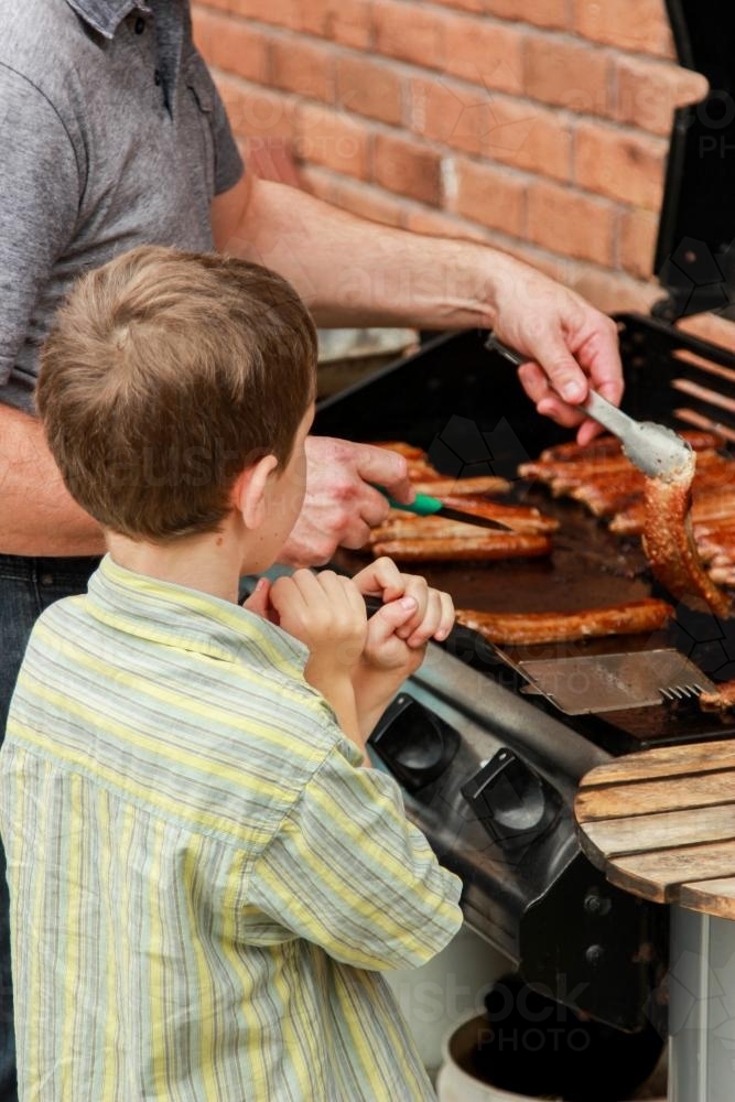 Image of Father and son cooking sausages on the BBQ toghther - Austockphoto