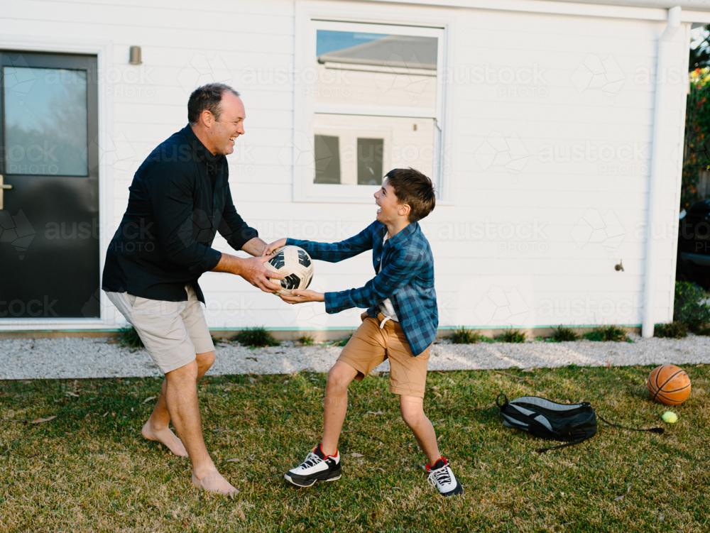 Image of Father and son playing with a soccer ball outside the house ...