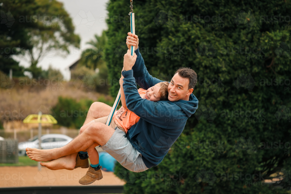 Image of Father and son riding flying fox together at the park ...