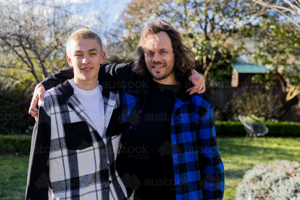 Image of father and son standing in the garden with arms over each ...