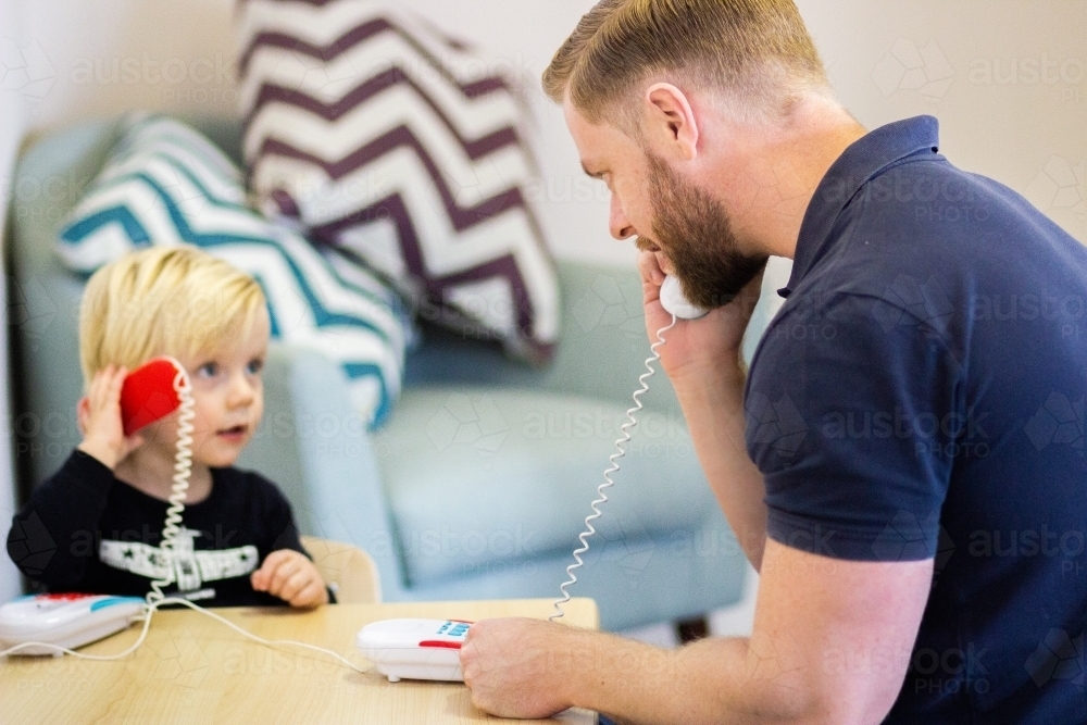Image of Father and son talking on toy phone - Austockphoto