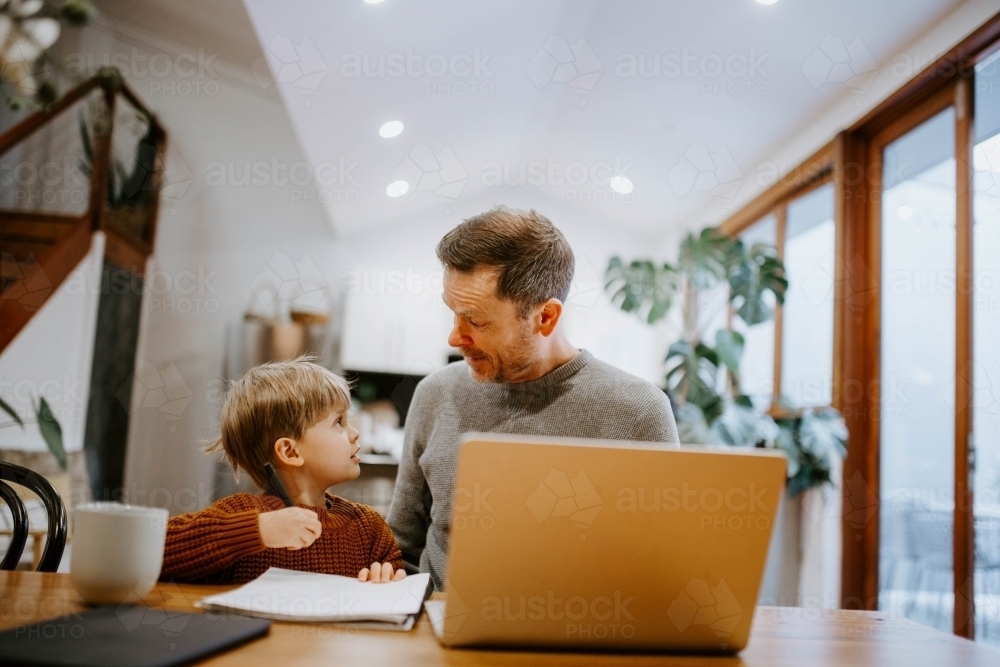 Image of Father and young son doing homework together at table ...