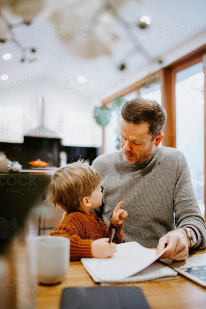 Image of Father and young son doing homework together at table ...