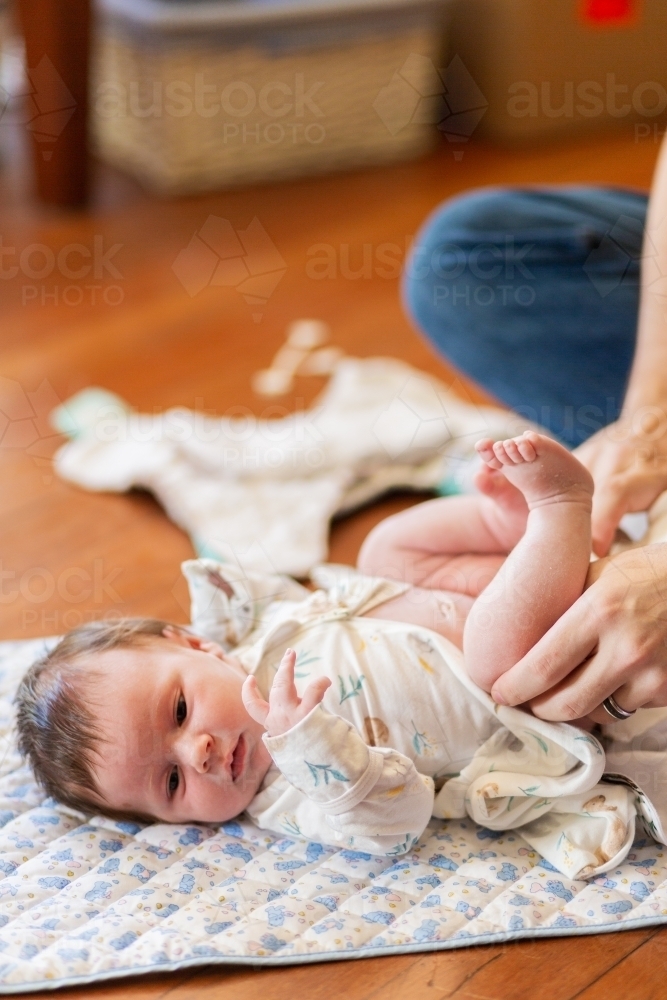 Image of Father changing newborn baby's nappy on the floor - Austockphoto