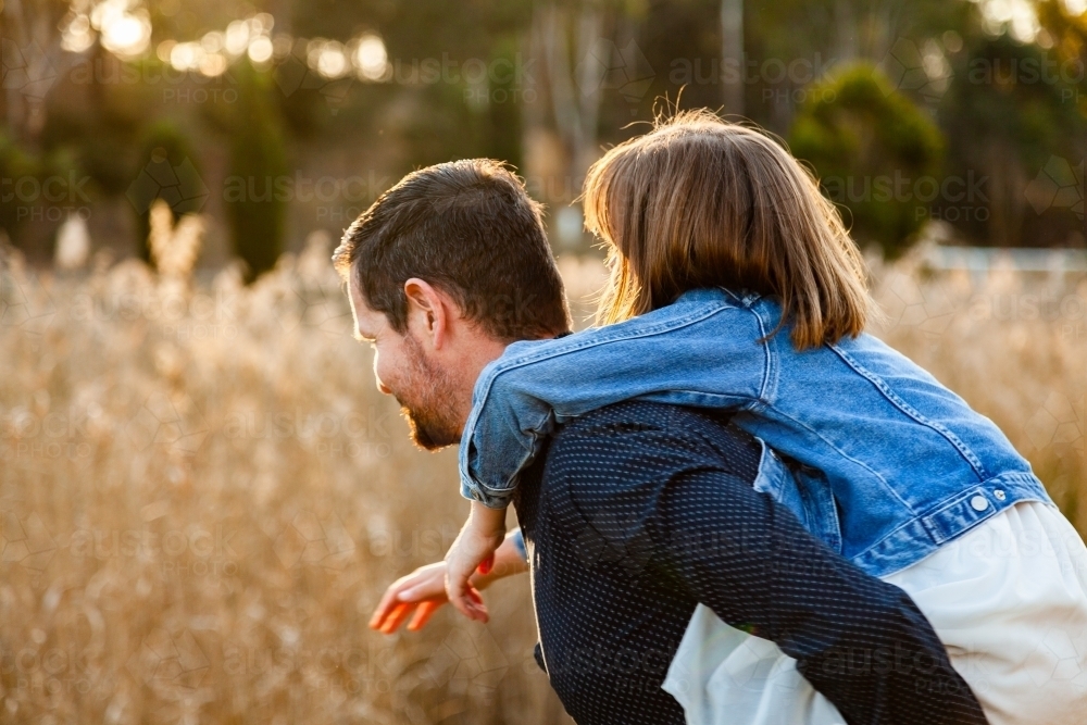 Image of Father giving daughter a piggy back ride - Austockphoto