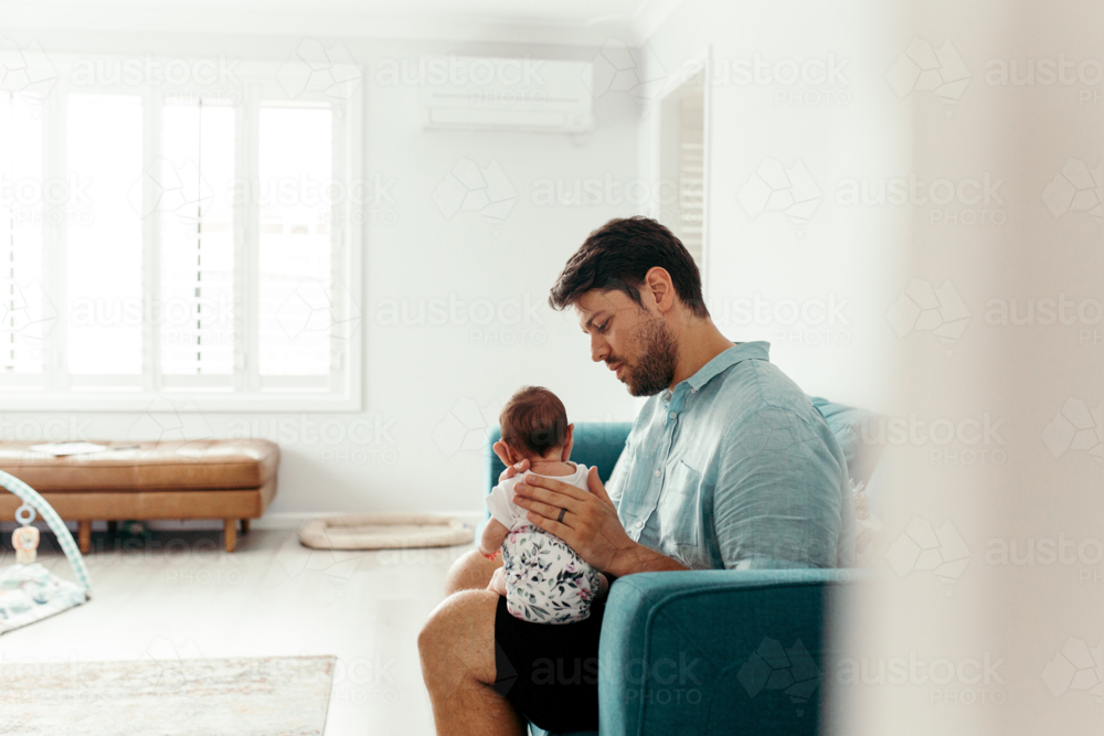 Image of Father holding newborn baby upright in the living room ...