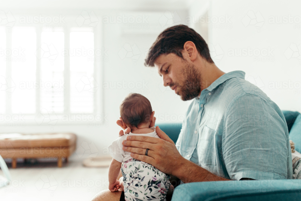 Image of Father holding newborn baby upright in the living room ...
