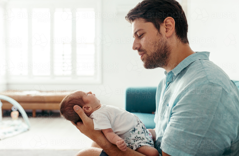 Image of Father holding newborn baby upright in the living room ...