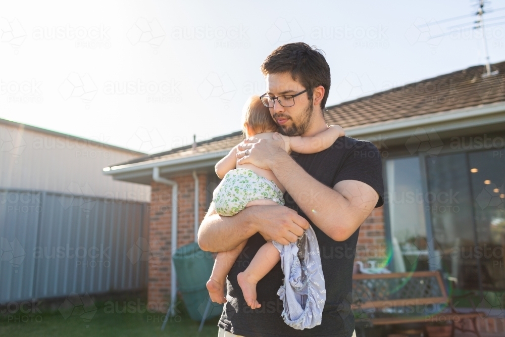 Image of Father hugging child after fun playing outside and getting wet ...