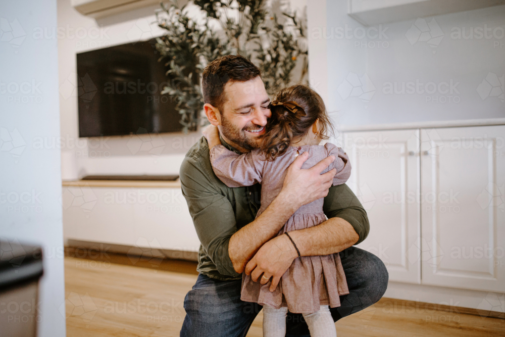 Image of Father hugging toddler daughter inside home - Austockphoto