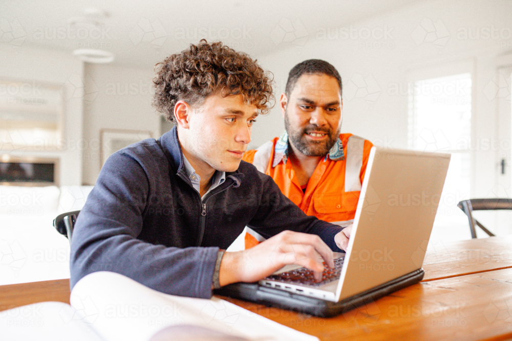 Image of Father in high vis clothing helping teenage son with homework ...