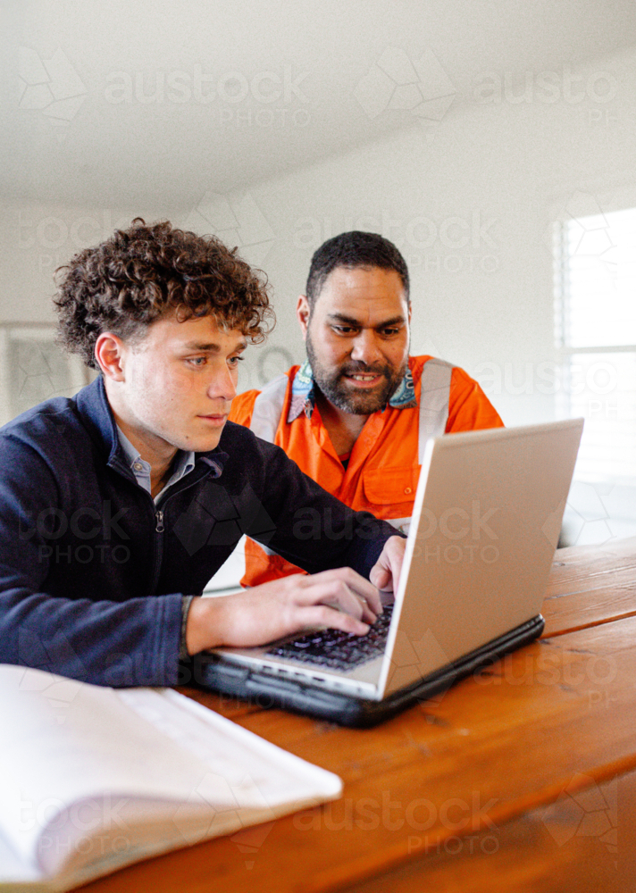 Image of Father in high vis clothing helping teenage son with homework ...