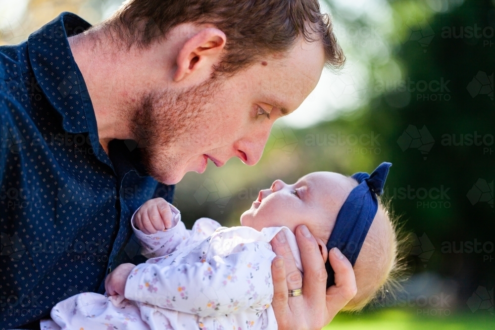 Image of Father singing to baby girl outside in garden in spring ...