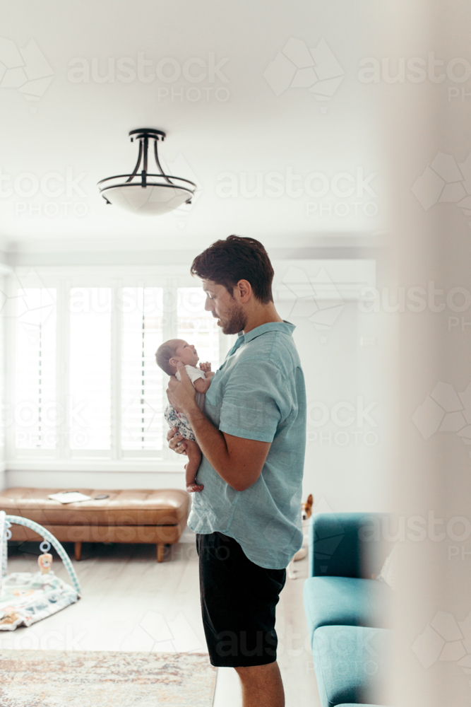 Image of Father standing holding newborn baby upright in the living ...
