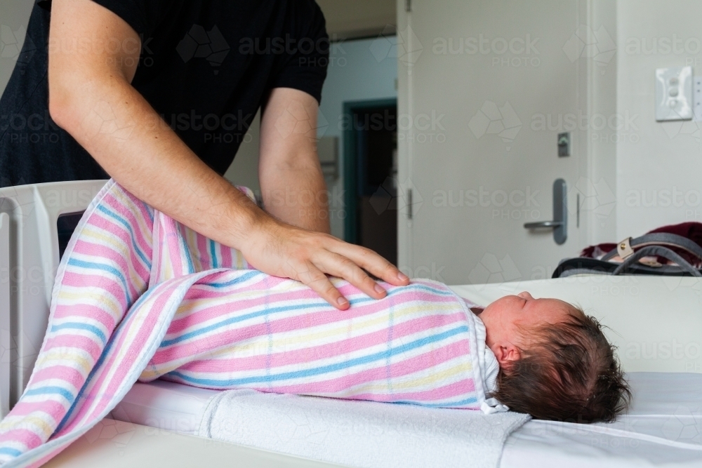 Image of Father wrapping up day old newborn baby in hospital blanket ...