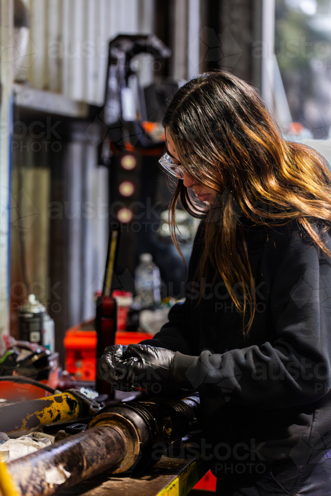 Image of Female Australian mechanic working on vehicle driveshaft joint ...