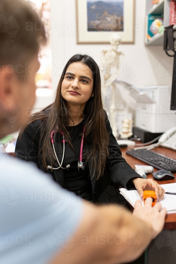 Image of Female doctor checking a male patient's pulse with an oximeter ...