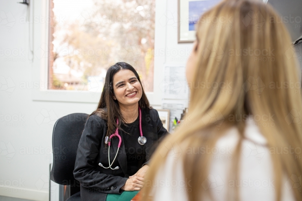 Image of Female doctor smiles as she listens to her female patient ...