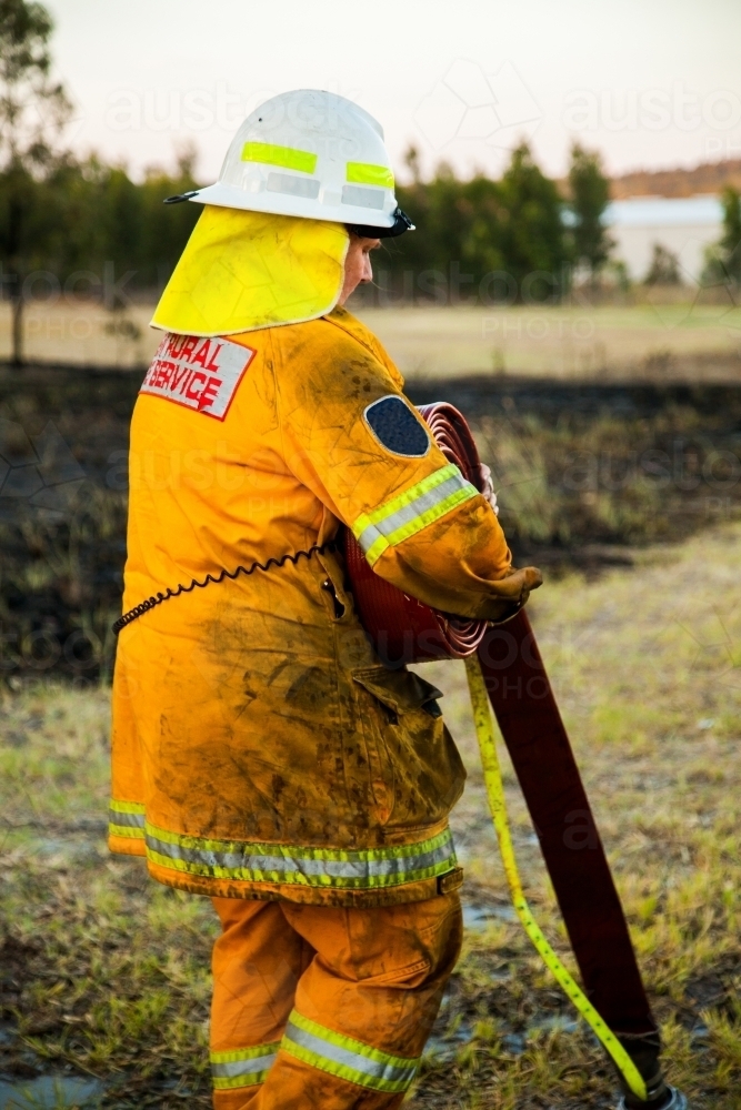 Image of Female firefighter rolling up hose and packing it away after ...