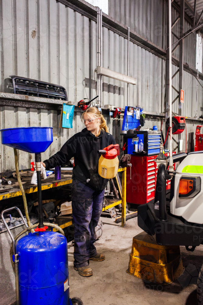 Image of female mechanic getting ready to fill up car with oil in ...