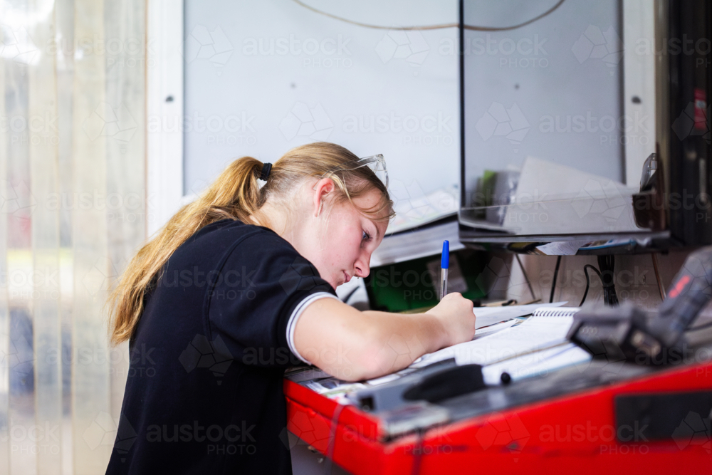 Image of female mechanic writing on timesheet - Austockphoto
