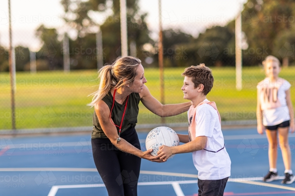 Image of female netball coach encouraging a kid on the court who is ...
