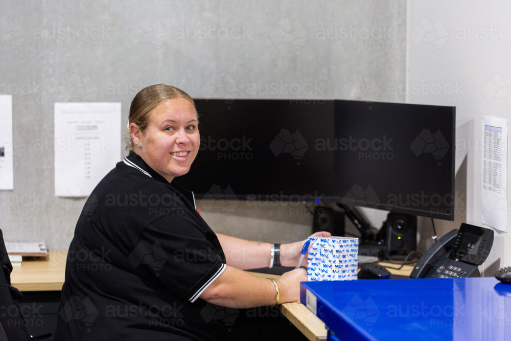 Image of Female office staff seated behind office desk in front of ...