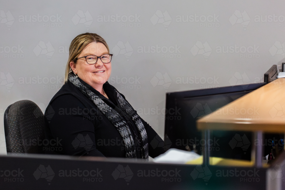 Image of Female office staff seated behind reception desk in front ...