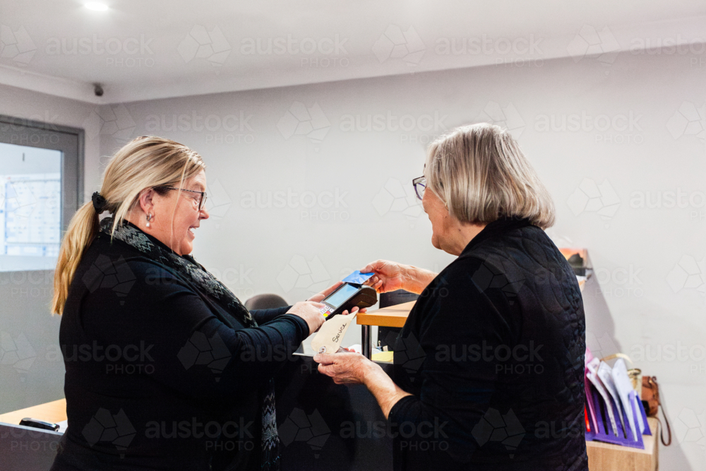 Image of Female office staff showing holding eftpos machine for payment ...