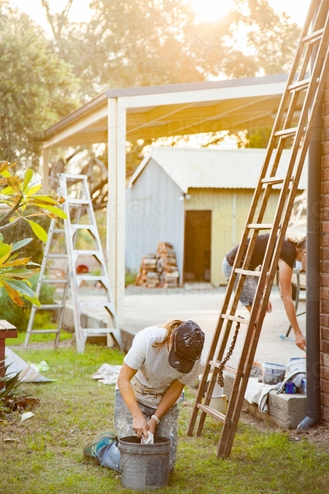 Image of Female painter cleaning brushes after days work - Austockphoto