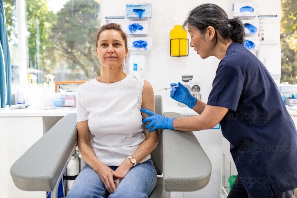 Image of Female patient getting an injection on the arm by a female ...