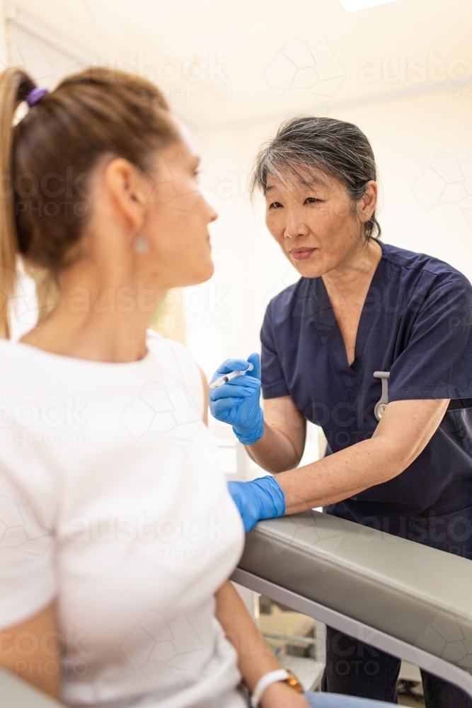 Image of Female patient getting an injection on the arm by a female ...