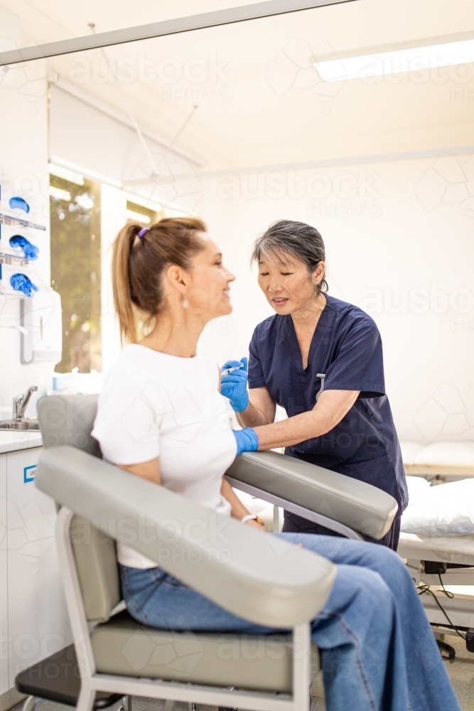 Image of Female patient getting an injection on the arm by a female ...