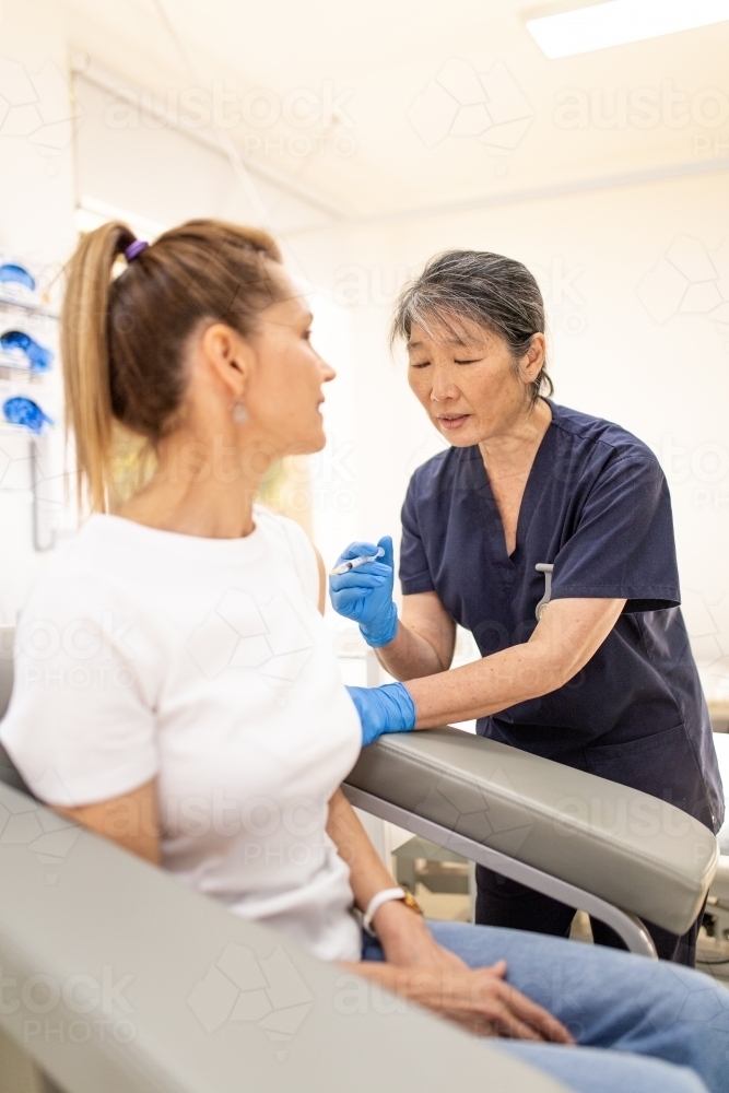 Image of Female patient getting an injection on the arm by a female ...