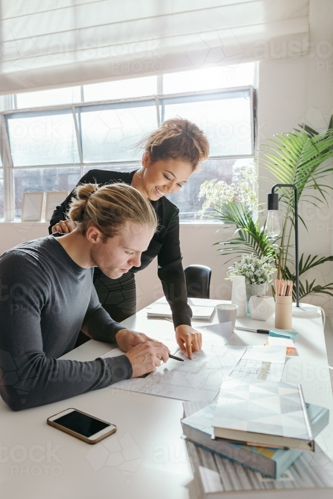 Image of Female professional looking over the plans of a co-worker ...
