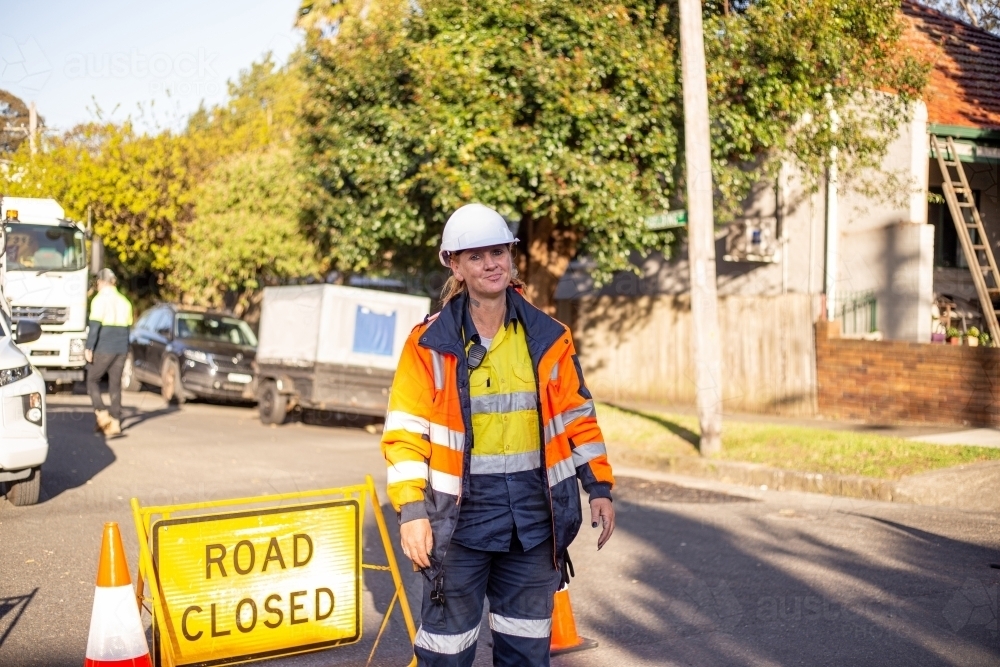 Image of Female road worker wearing white helmet and orange jacket on ...