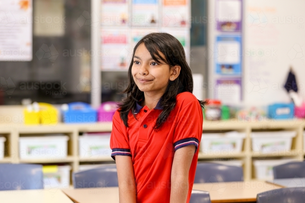 Image of Female school student in a red polo shirt thoughtfully ...