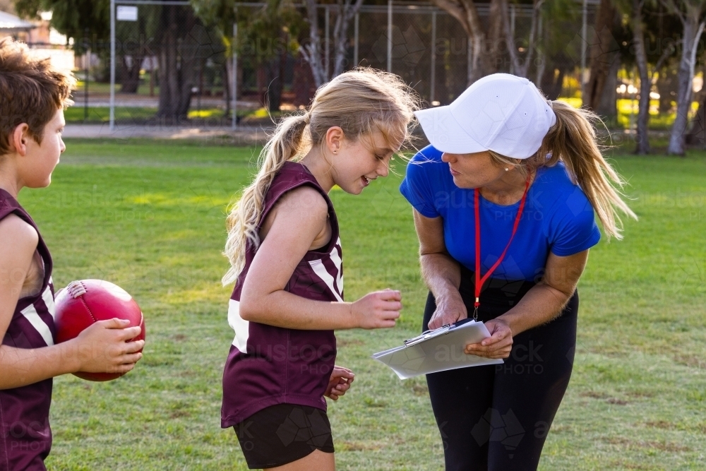 Image of female sports coach interacting with young girl football ...
