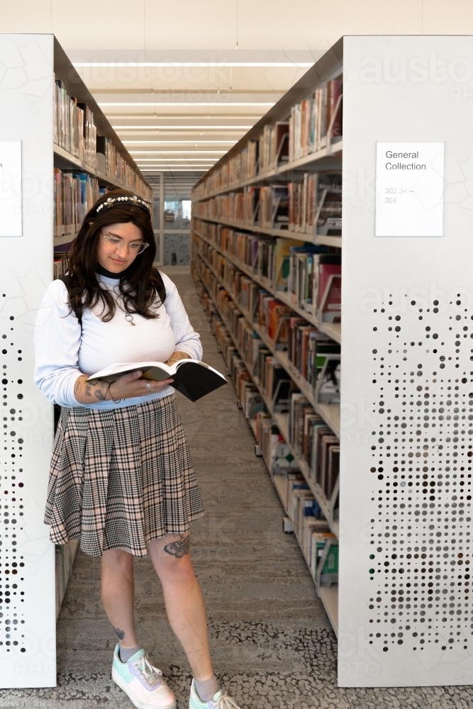 Image of Female Student Browsing and reading Book Amongst Library ...