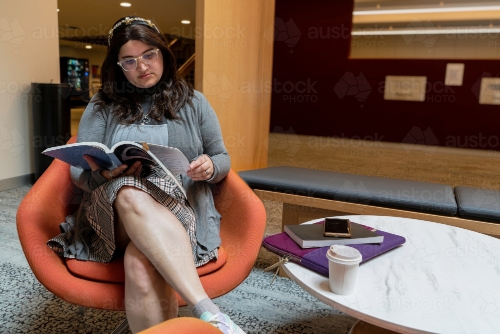 Image of Female Student Seated while Reading Indoors - Austockphoto