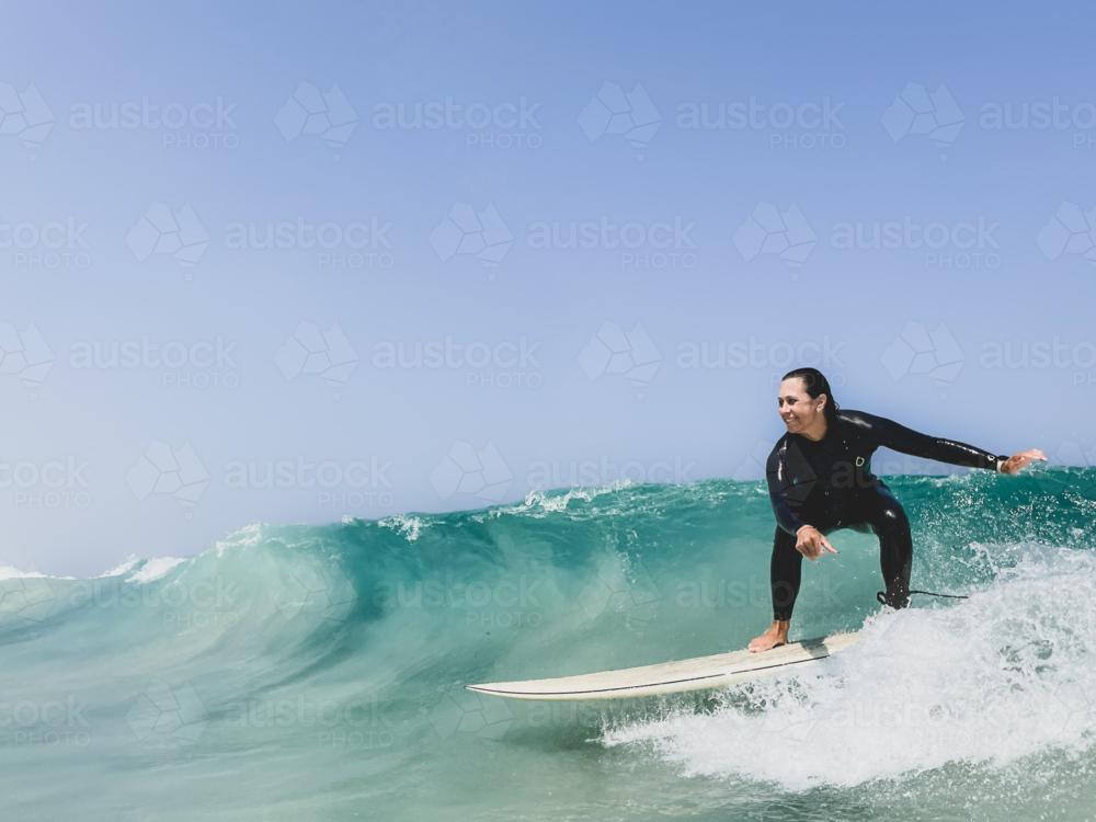 Image of Female surfer in steamer wetsuit surfing clean green wave ...